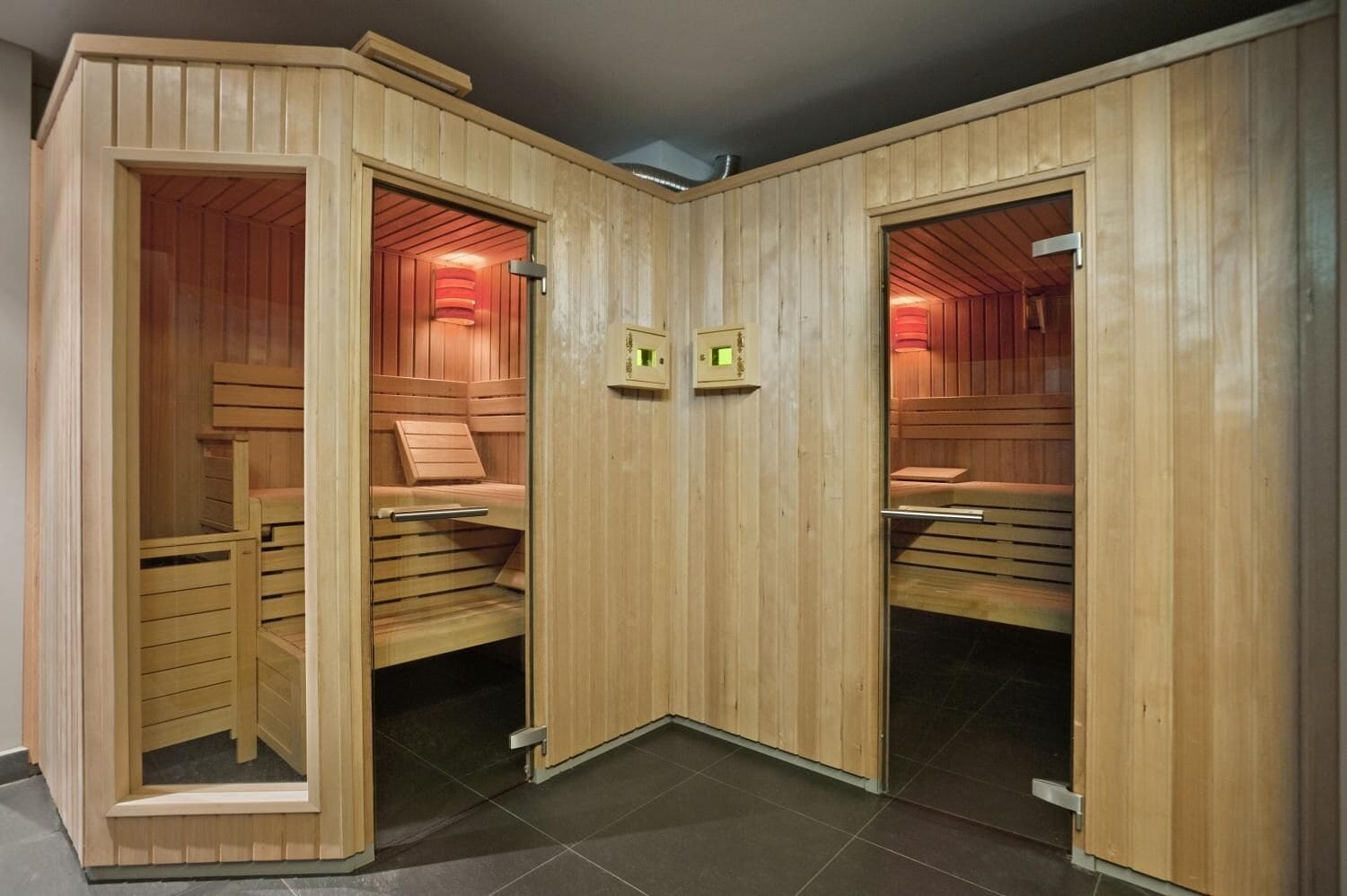 Uma sauna com duas bancas de madeira e uma porta.