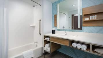 Uma casa de banho moderna com cabine de duche, um espelho grande, toucador com lavatório e prateleiras com toalhas.