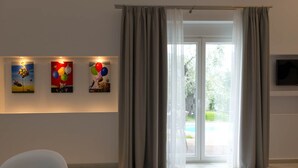 Sala de estar moderna com uma grande porta de vidro deslizante que dá para um jardim. Há três quadros pendurados na parede retratando balões.