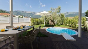 Um pátio externo com piscina, mesa de jantar e cadeiras.