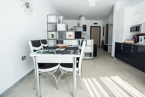 Cozinha moderna com armários brancos, micro-ondas e máquina de café.