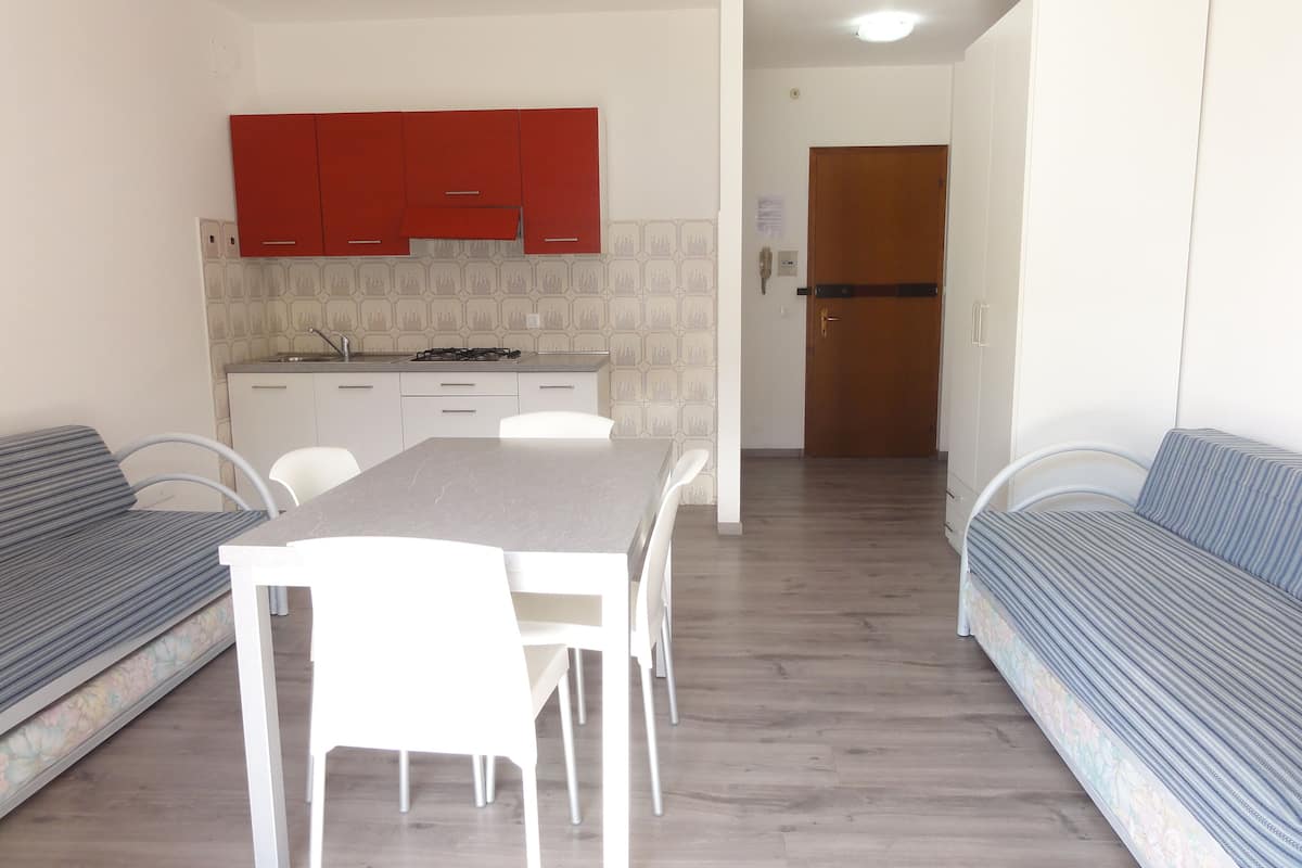 Um espaço compacto com cozinha, mesa de jantar e cadeiras, e um sofá.