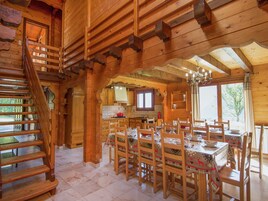 Interior de uma cabana de madeira com sala de jantar, cozinha e escada.