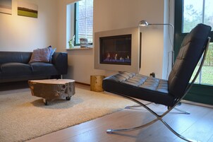 Uma sala de estar moderna com lareira, um sofá, uma mesa de centro e uma poltrona.