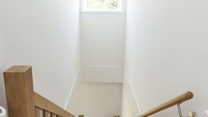 Escada com grades de madeira e uma janela no topo.