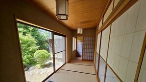 Um interior japonês tradicional com tatames, portas deslizantes e vista para um jardim.