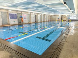 Piscina interior extensa com faixas delimitadoras e placas de segurança.