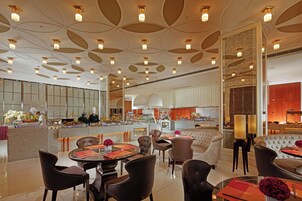 Um amplo hall de hotel com um bar central, diversas áreas de estar e um design de teto moderno.