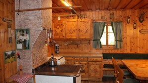 Uma cabana de madeira rústica com cozinha, incluindo fogão, armários e mesa de jantar com cadeiras.