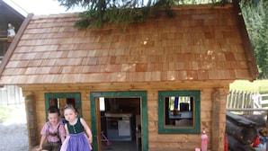 Uma casinha de brincar de madeira com telhado inclinado e porta da frente.