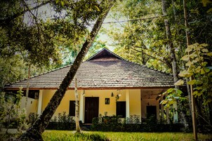 Uma casa com telhado de cerâmica, rodeada por vegetação e árvores.