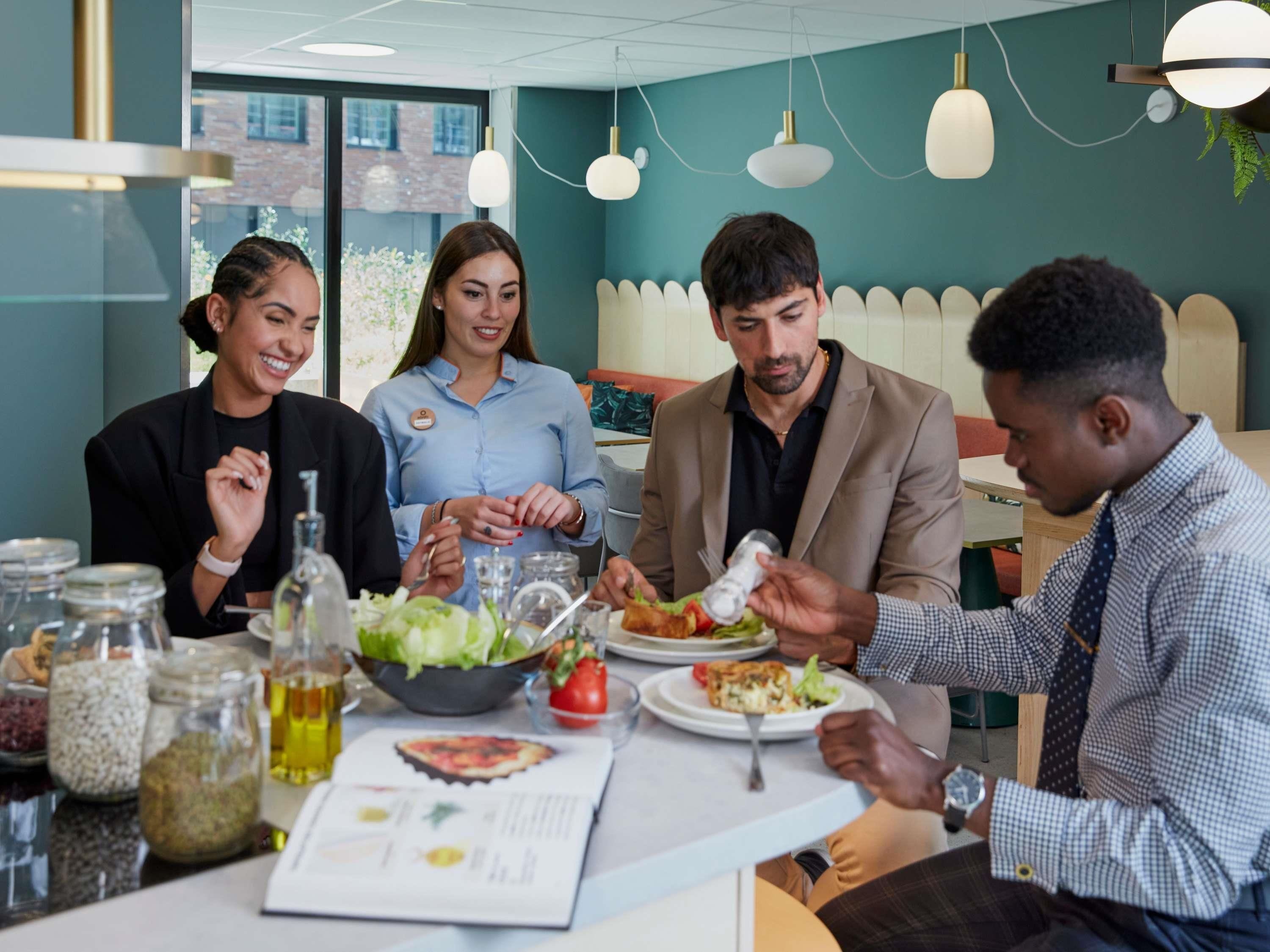 Um grupo de pessoas jantando à mesa, com diversos pratos, um cardápio e acompanhamentos.