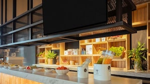 Uma área de bar moderna com bancada de mármore, cadeiras de madeira e uma televisão montada acima.