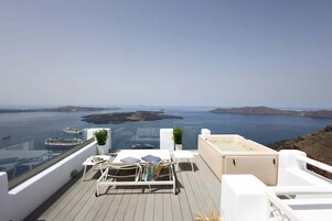 Terraço com mobiliário branco, guarda-corpo de vidro e vista para o mar e ilhas.