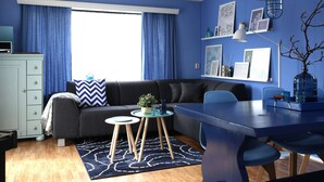 Uma sala de estar moderna com um sofá, uma mesa de jantar e uma parede azul destacada.