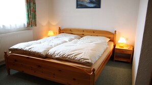 Uma cama de madeira com duas almofadas e duas mesas de cabeceira com abajures.