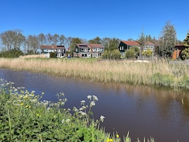 Área residencial com casas ao longo de um corpo d'água, cercada por vegetação.