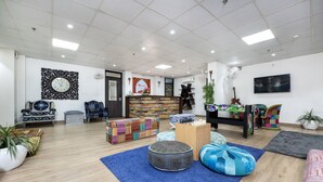 Um hall amplo com balcão de recepção, sofás, mesa de centro e um violão.