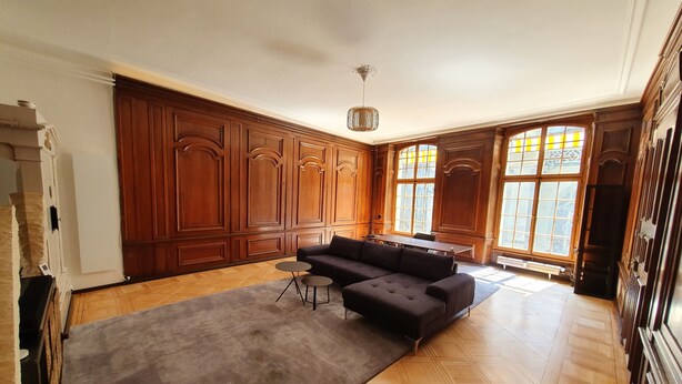 Um quarto espaçoso com um grande armário de madeira, um sofá escuro e uma mesa de jantar.
