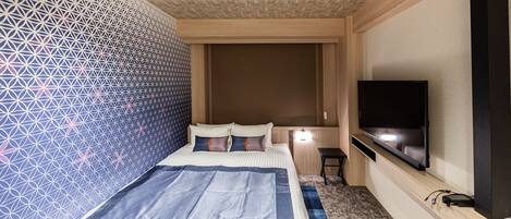 Quarto de hotel com cama, televisão e parede estampada.