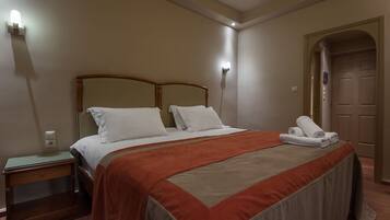 Quarto de hotel com cama, mesa de cabeceira, luminária na parede e porta.