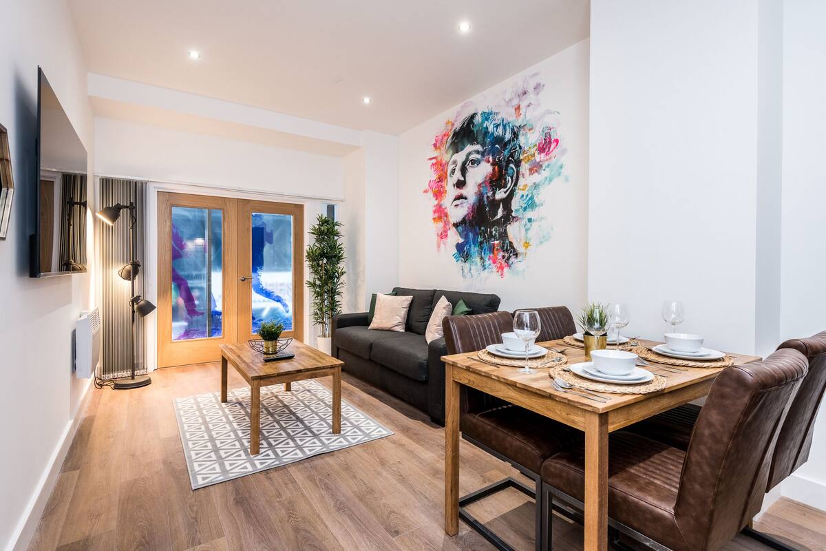 Uma sala de estar moderna com área de jantar, uma grande pintura abstrata e uma porta de vidro deslizante que dá para uma varanda.