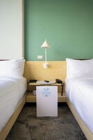 Quarto de hotel com duas camas, uma pequena mesa de cabeceira, uma luminária, um telefone e um purificador de ar portátil.