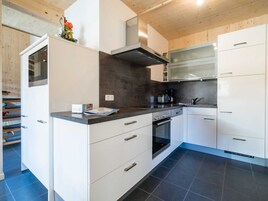 Uma cozinha moderna com armários brancos, bancada preta e coifa de aço inoxidável.