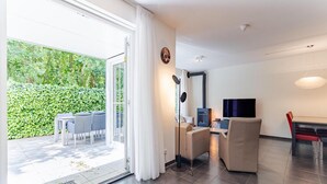 Uma sala de estar moderna com uma porta de vidro deslizante que dá para uma área externa, lareira e um espaço de jantar.