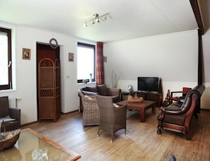 Sala de estar com sofá, poltrona, televisão e uma mesinha.