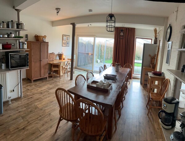 Cozinha espaçosa com armários de madeira, uma mesa de jantar e cadeiras. Uma grande janela oferece vista para o exterior.