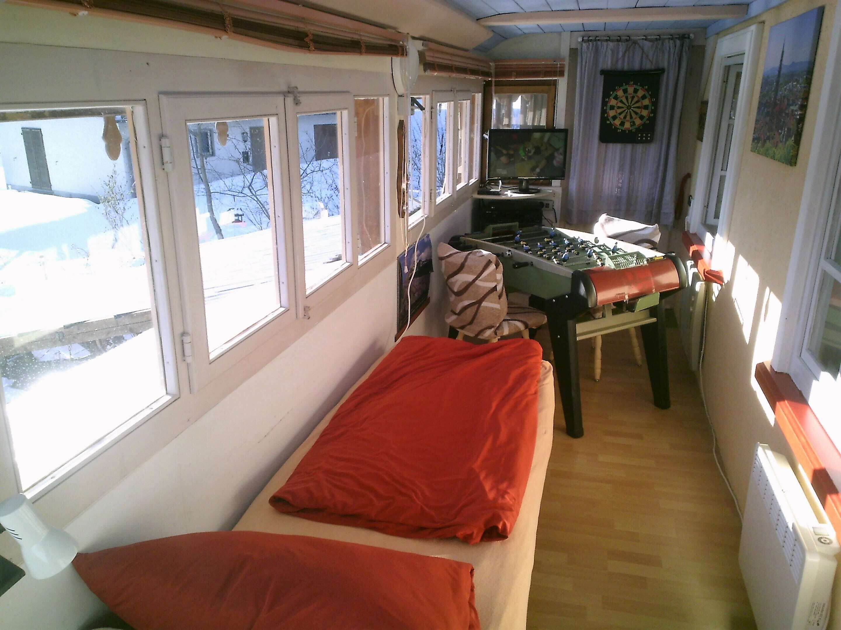 Um quarto com mesa de pebolim, televisão e alvo de dardos.