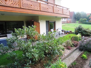 Uma casa moderna com varanda, um pátio com móveis de exterior e um jardim bem cuidado.