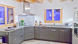 Uma cozinha moderna com armários cinzas, bancada de mármore e forno embutido.