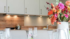 Mesa posta com copos de vinho, pratos e um vaso de flores.