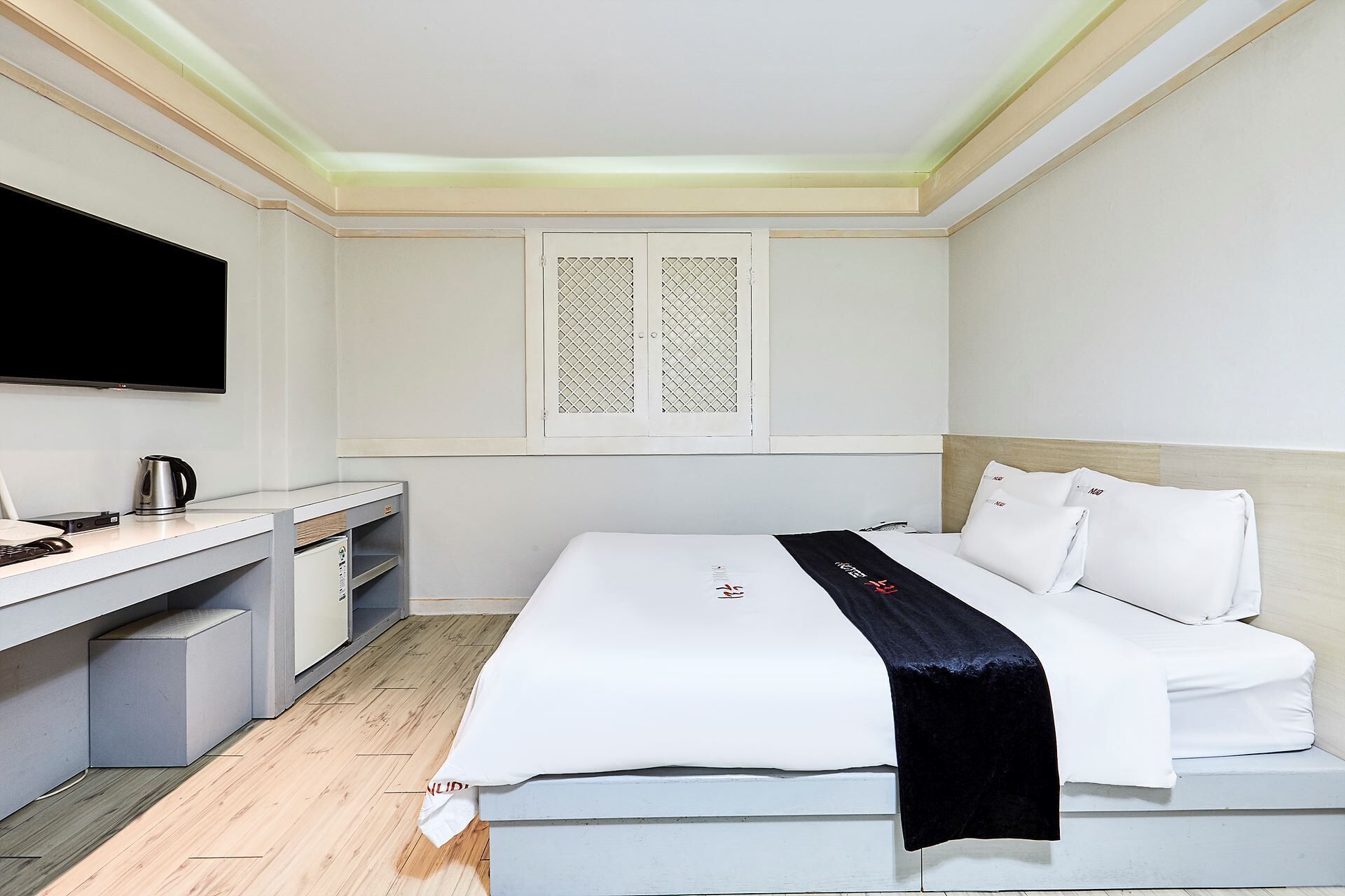 Quarto de hotel com cama, escrivaninha, televisão e janela com vista.