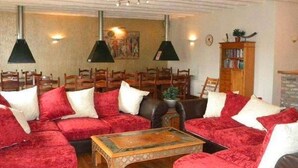 Uma sala de estar acolhedora com sofás de veludo vermelho, uma mesa de centro de madeira e uma estante.