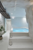 Uma área de spa moderna com hidromassagem, degraus de acesso e uma planta em vaso.