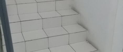 Escada com azulejos brancos e corrimão de metal.