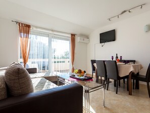 Uma sala de estar moderna com um sofá, uma mesa de centro de vidro e um espaço de jantar com mesa e cadeiras.