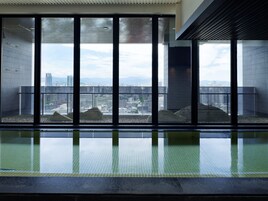 Piscina interior moderna com amplas janelas que oferecem vista para a cidade.