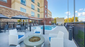 Uma área de piscina de hotel com mobiliário de exterior e lareira.