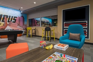 Uma área de lounge moderna com mesa de bilhar, assentos coloridos e diversos jogos de tabuleiro.