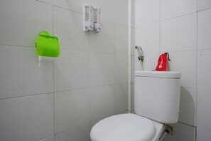 Um vaso sanitário branco com uma sacola vermelha pendurada na parede ao lado.