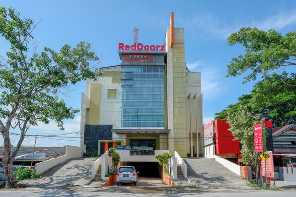 Um hotel chamado RedDoorz com design moderno, destacando uma entrada imponente e uma área de estacionamento visível.