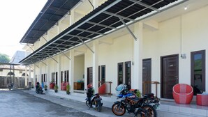 Um edifício com varanda coberta, várias portas e algumas motocicletas estacionadas na frente.