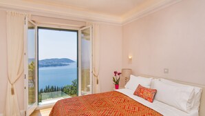 Um quarto com uma cama grande, vista para o mar e uma varanda.