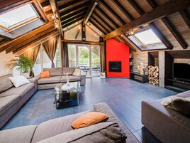 Um amplo loft com pé direito alto, lareira, sofá e televisão.