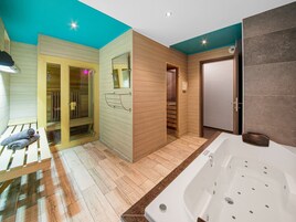 Uma casa de banho moderna com sauna de madeira, uma banheira grande e zona de duche.