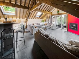 Quarto estilo sótão com teto alto, vigas de madeira aparentes, janela grande e uma parede de destaque vermelha.